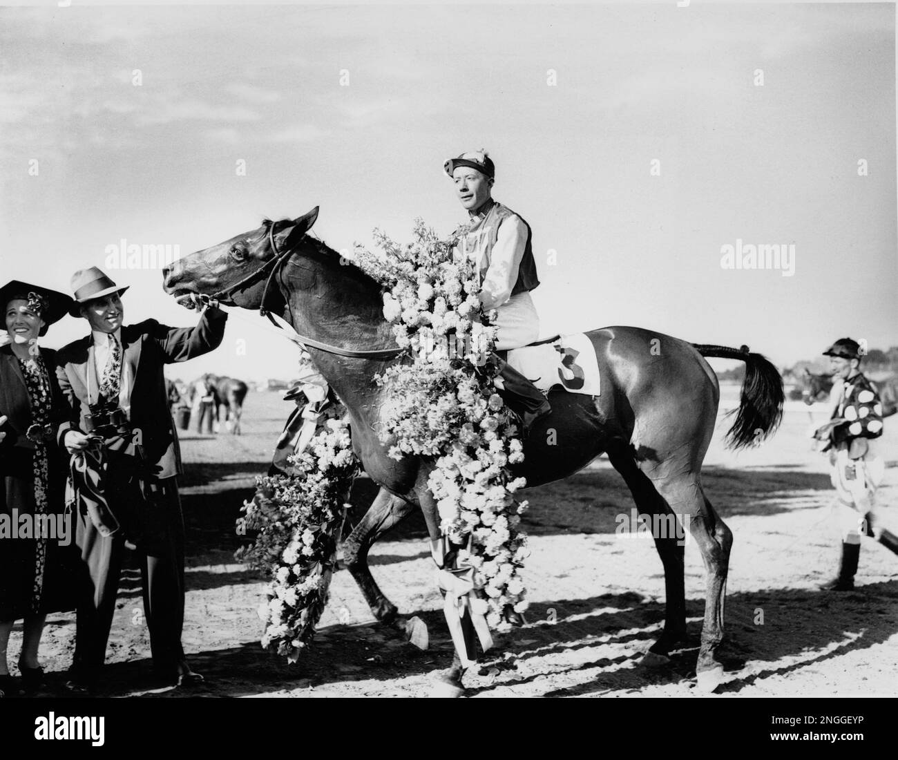 Seabiscuit, wearing the victory flower garland, is shown with jockey ...