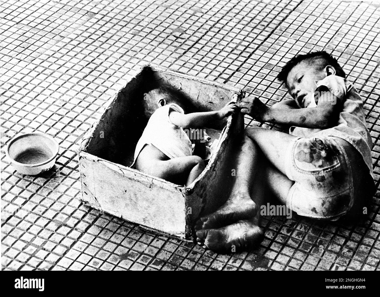 Tran Thie Het Nhanny lies in a cardboard box next to her brother, who ...