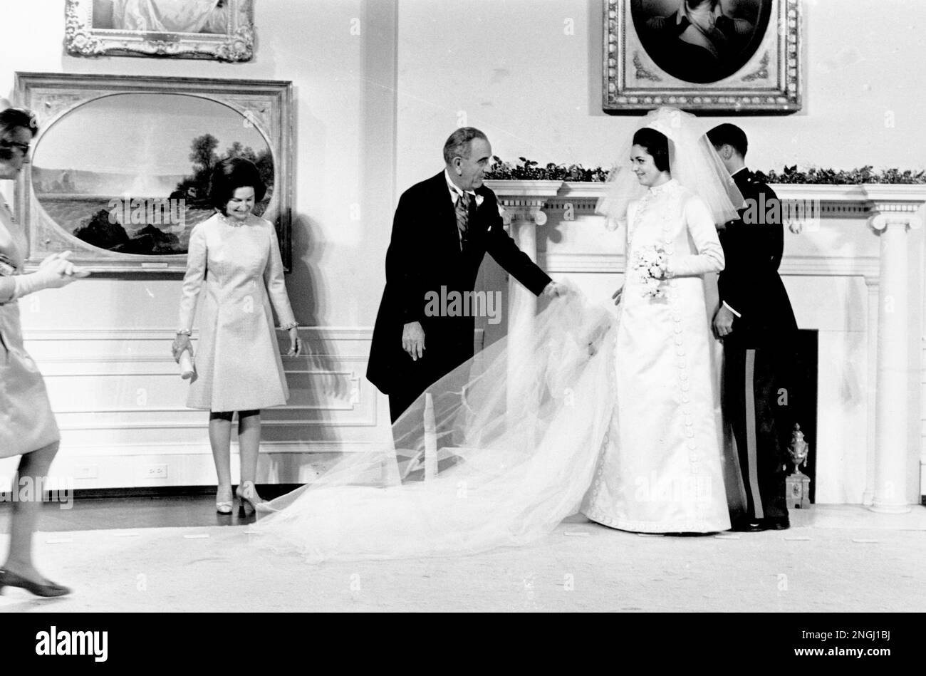 U.S. President Lyndon B. Johnson helps adjust the wedding gown train of ...