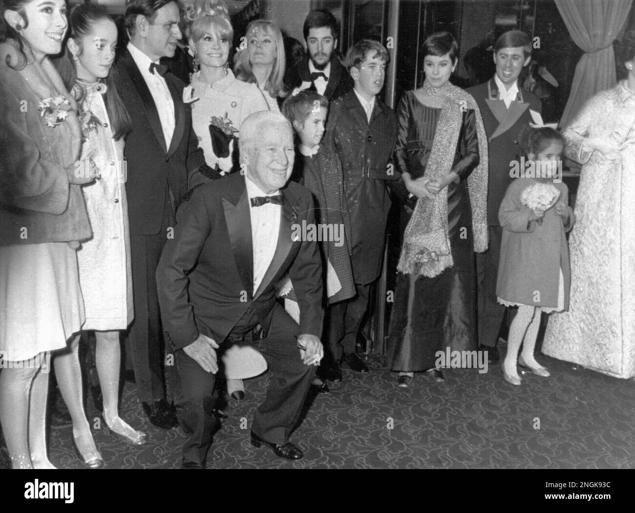 Actor and producer Charles Chaplin does a knee bend as he arrives with ...