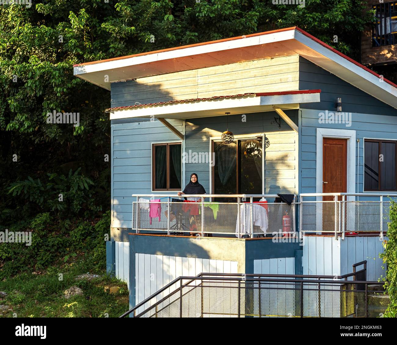 Eine ältere malaiische Frau in einem Hidschab steht auf dem Balkon ihres Zimmers im Kuak Hill ...