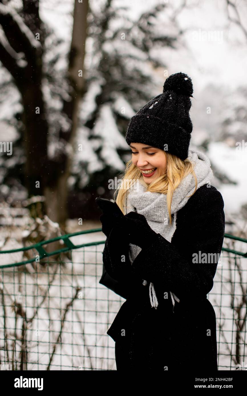 Eine junge Frau, die warme Winterkleidung trägt und eine Strickmütze ...