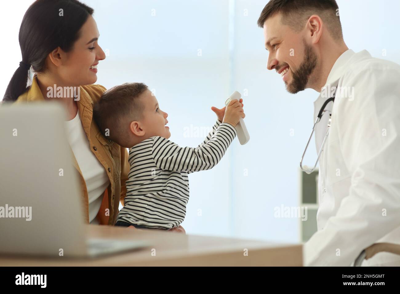 Mutter und Sohn beim Kinderarzt im Krankenhaus. Doktor spielt mit dem ...