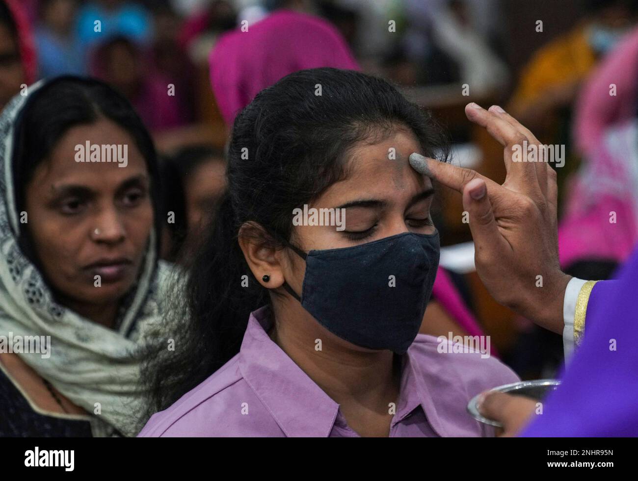 A Catholic priest marks the forehead of a devotee with the symbol of a ...