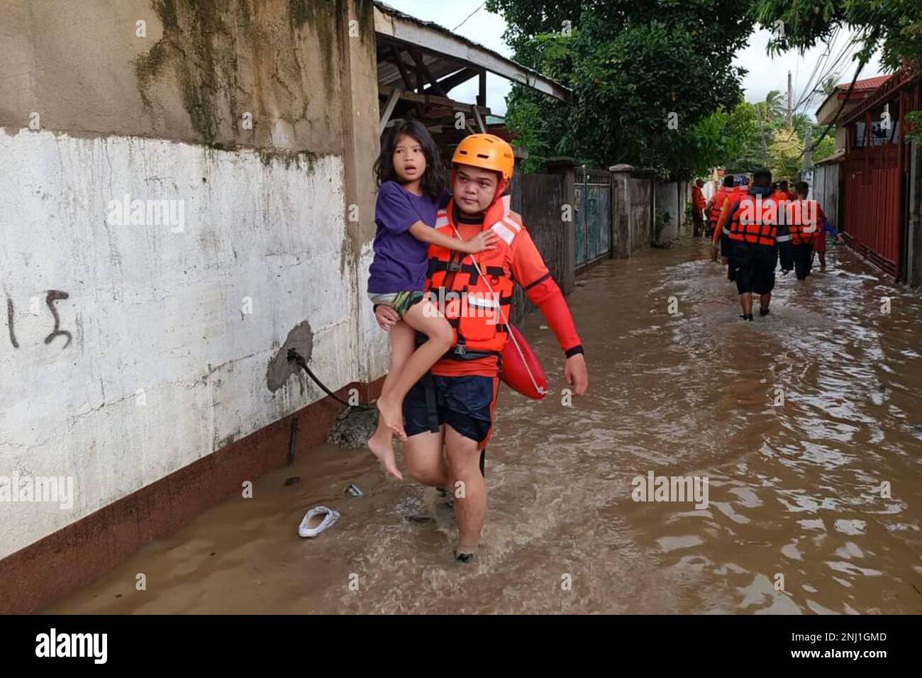 In this photo provided by the Philippine Coast Guard, a rescuer carries a girl over flood waters ...