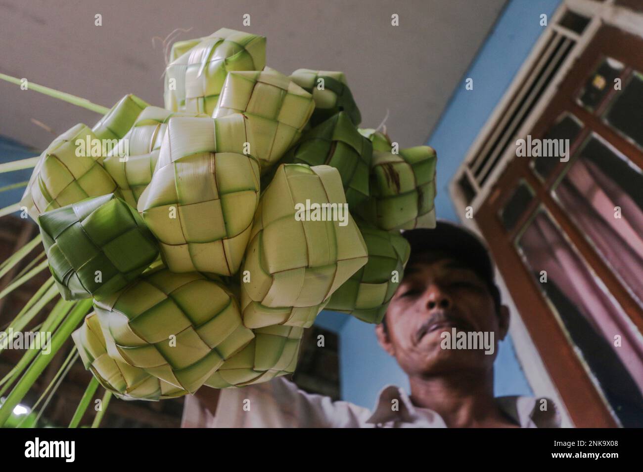 Indonesian vendors weave palm leaves used to make traditional rice ...