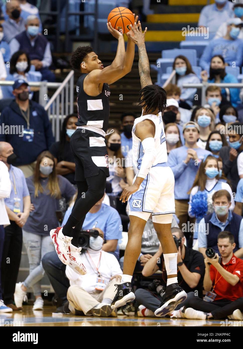 Louisville's Noah Locke, left, shoots a 3-point basket as North ...