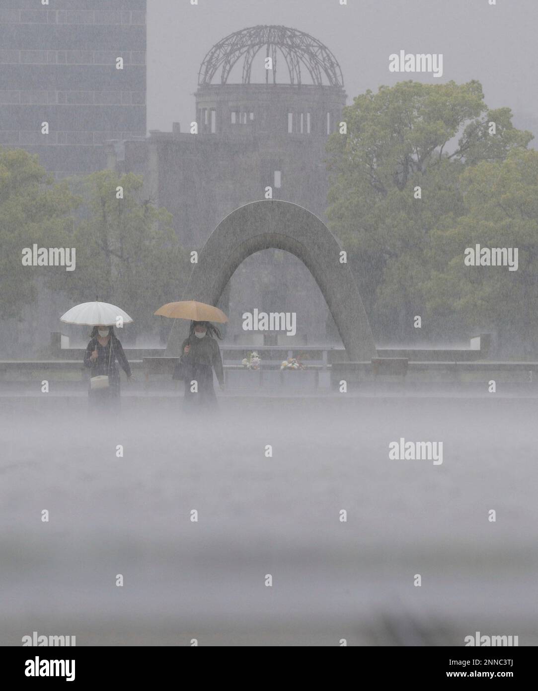 People under an umbrella walk in the heavy rain with Hiroshima Atomic ...