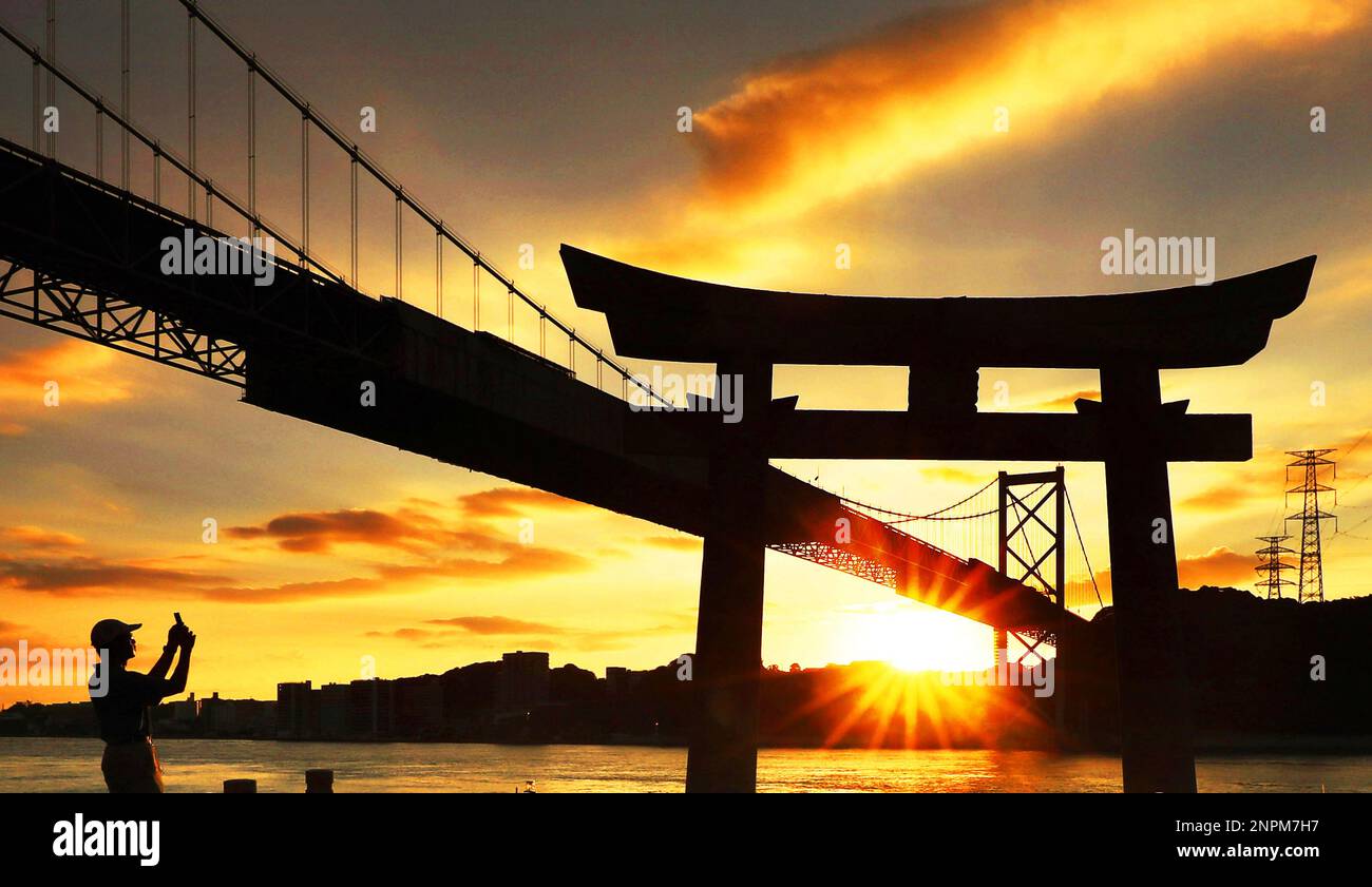 A photo shows a sunset over the Kanmon Bridge and the entrance gate of ...