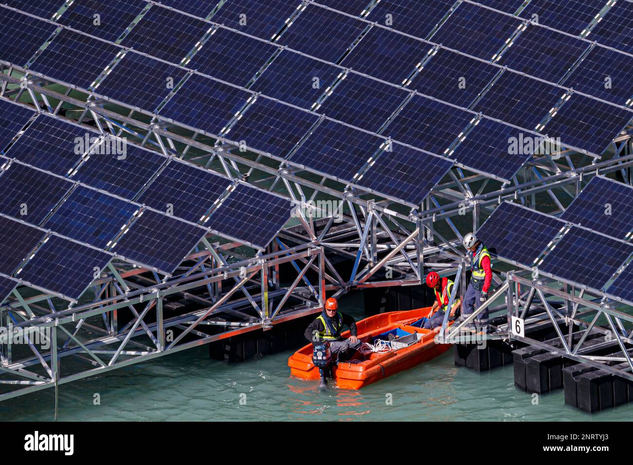 Workers assemble floating barges with solar panels on the 'Lac des ...