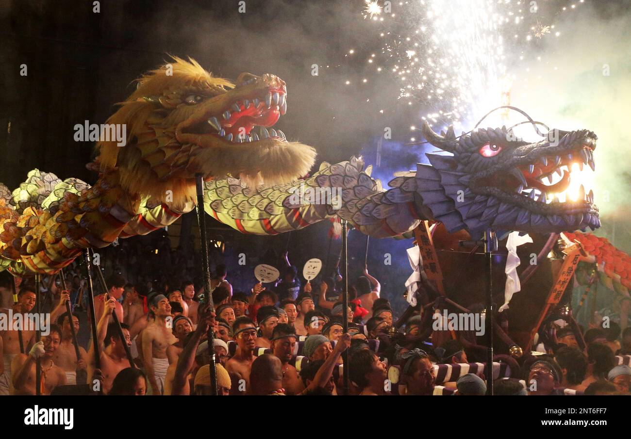 People clad in a loincloth carry a dragon float, portable shrine, and ...