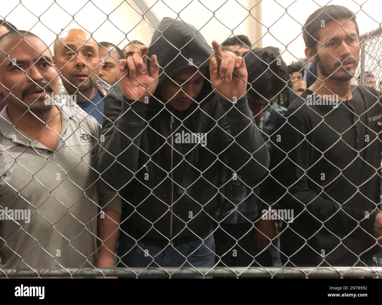 Men stand in a U.S. Immigration and Border Enforcement detention center ...