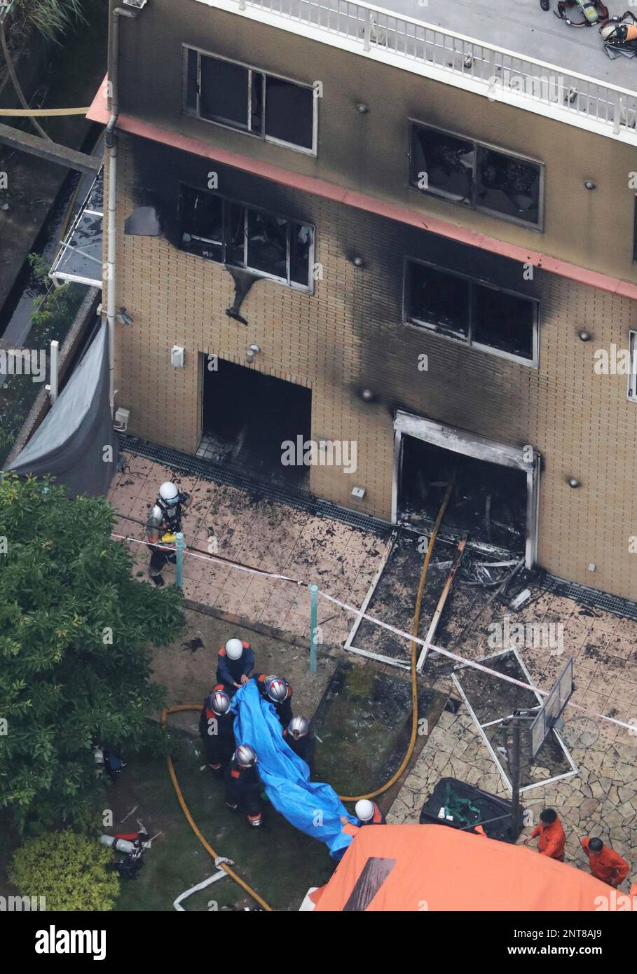 Police officers and fire fighters carry a dead body from the fire site ...