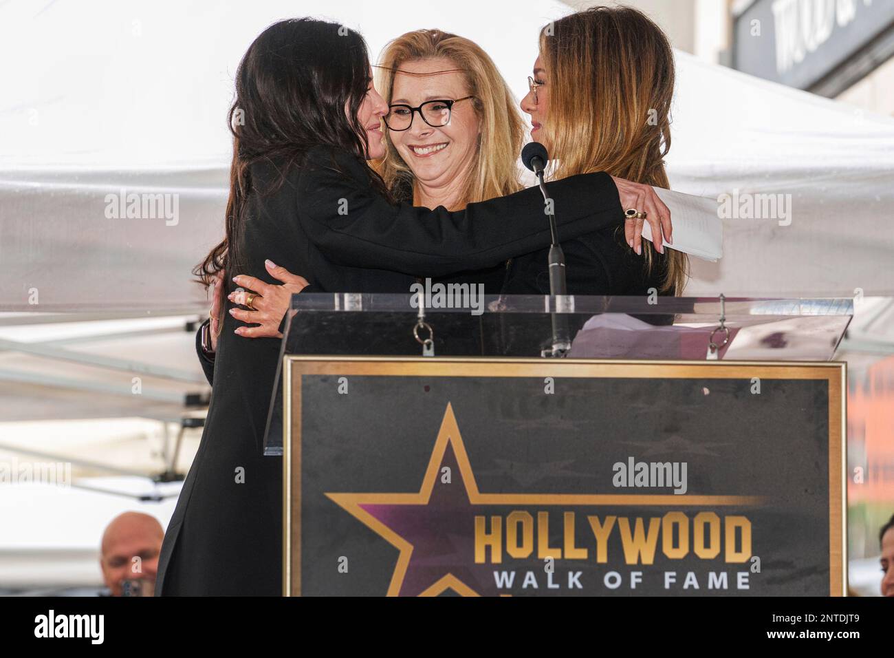 From left, actors, Courteney Cox, Lisa Kudrow and Jennifer Aniston hug ...