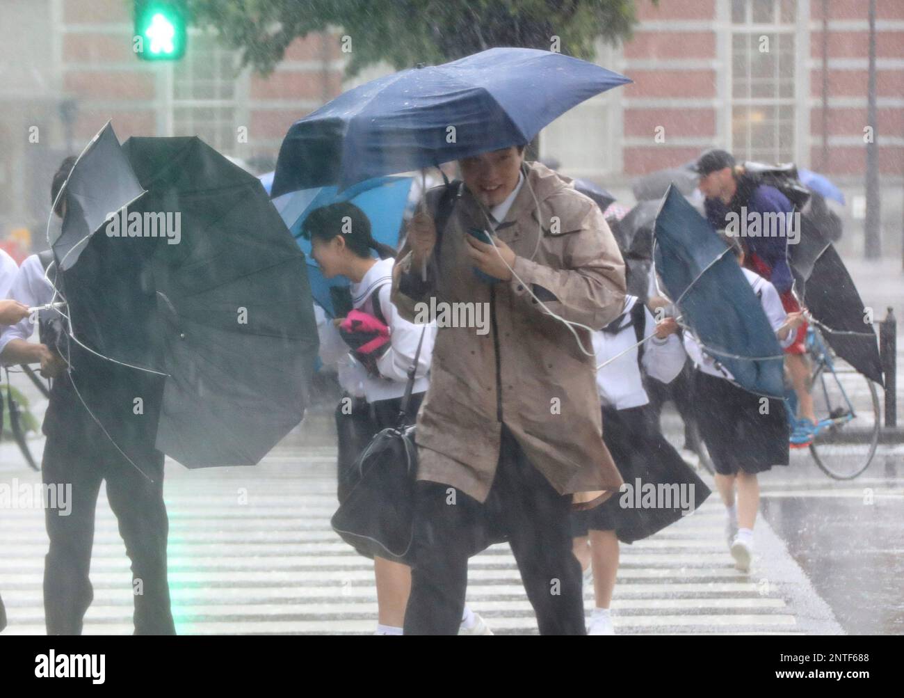 Pedestrians holding an umbrella struggle against a heavy rain and ...