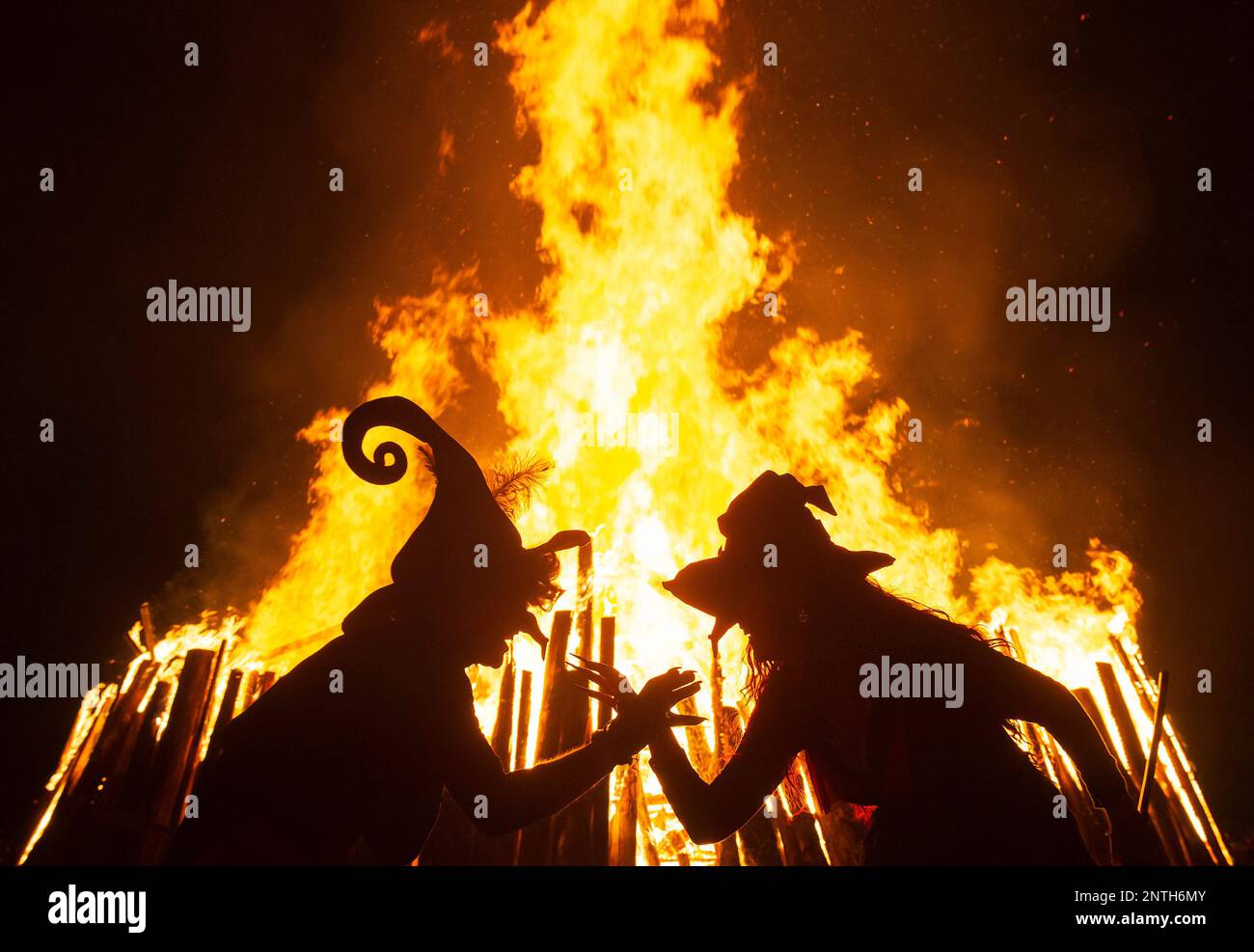 Women dressed as witches dance in front of the fire during the ...