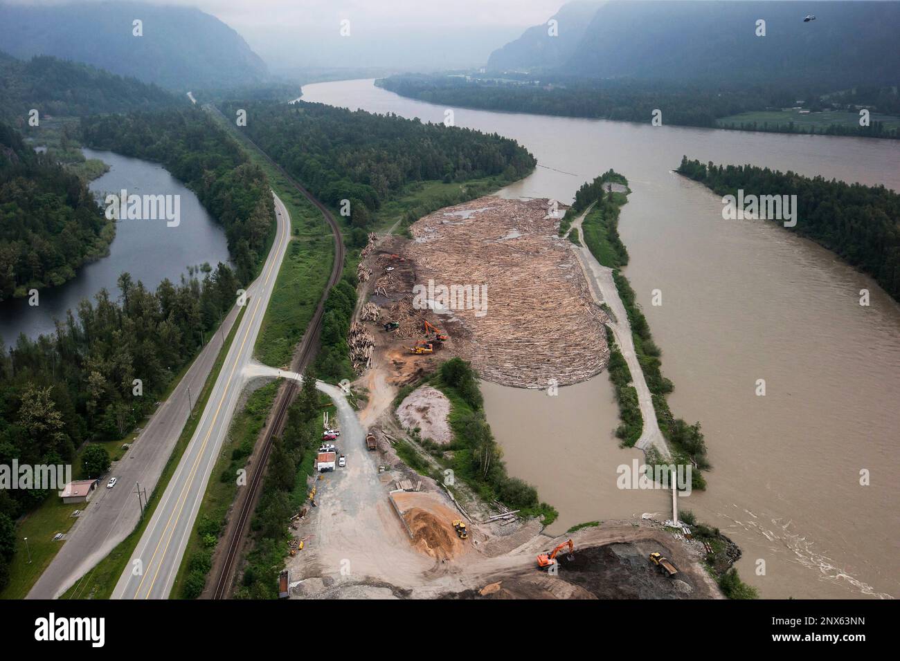 Workers use heavy equipment to clear logs from the Fraser River debris ...