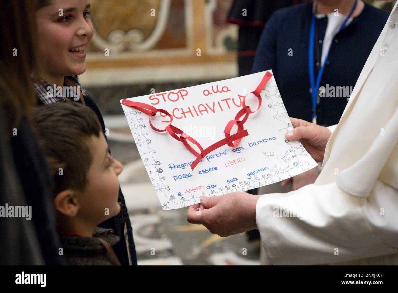 Pope Francis holds a sheet of paper reading in Italian "Stop Slavery ...