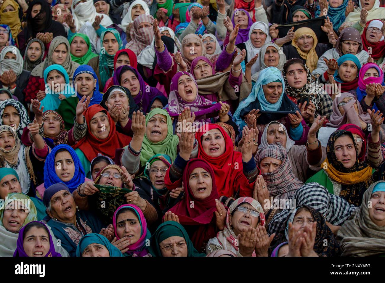 Kashmiri Muslim devotees raise their hands in prayer as a head priest ...