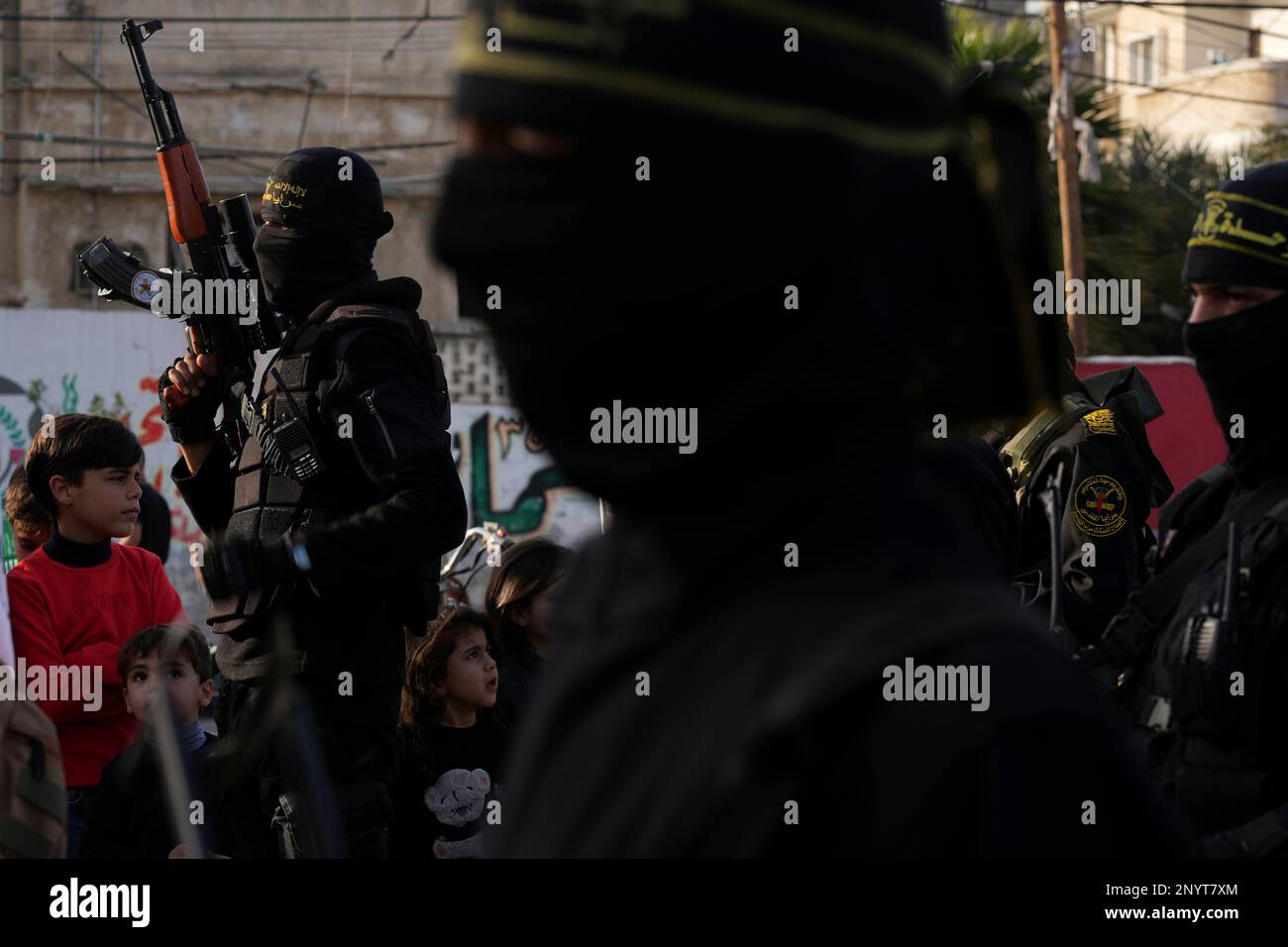 Palestinian children look at masked members of the Al-Quds Brigades ...