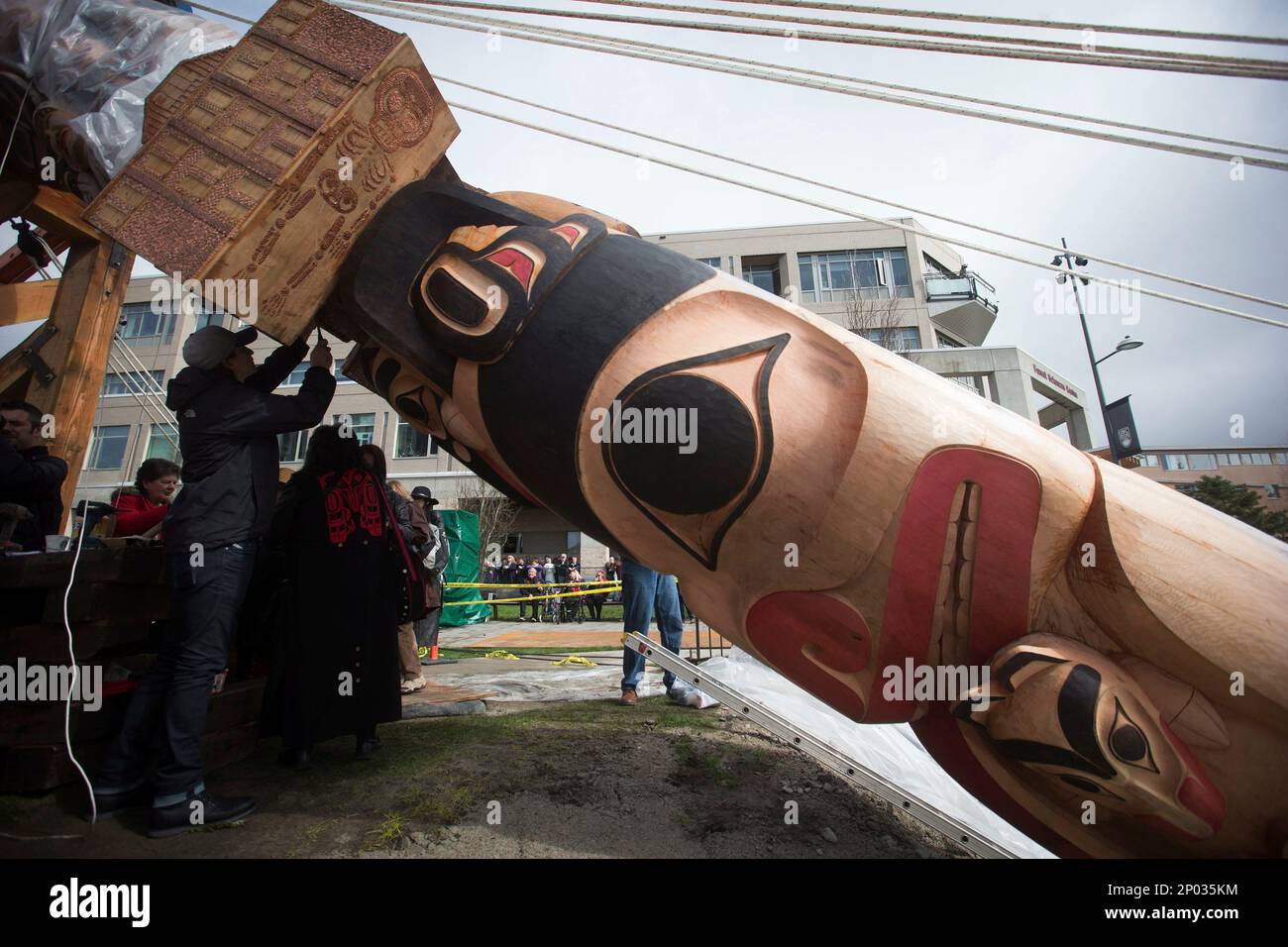 A man hammers a copper nail into the Reconciliation Pole before its ...