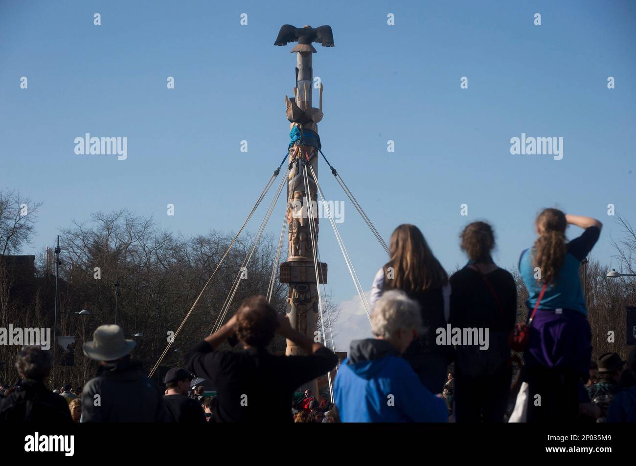 People watch as a Reconciliation Pole is raised at the University of ...