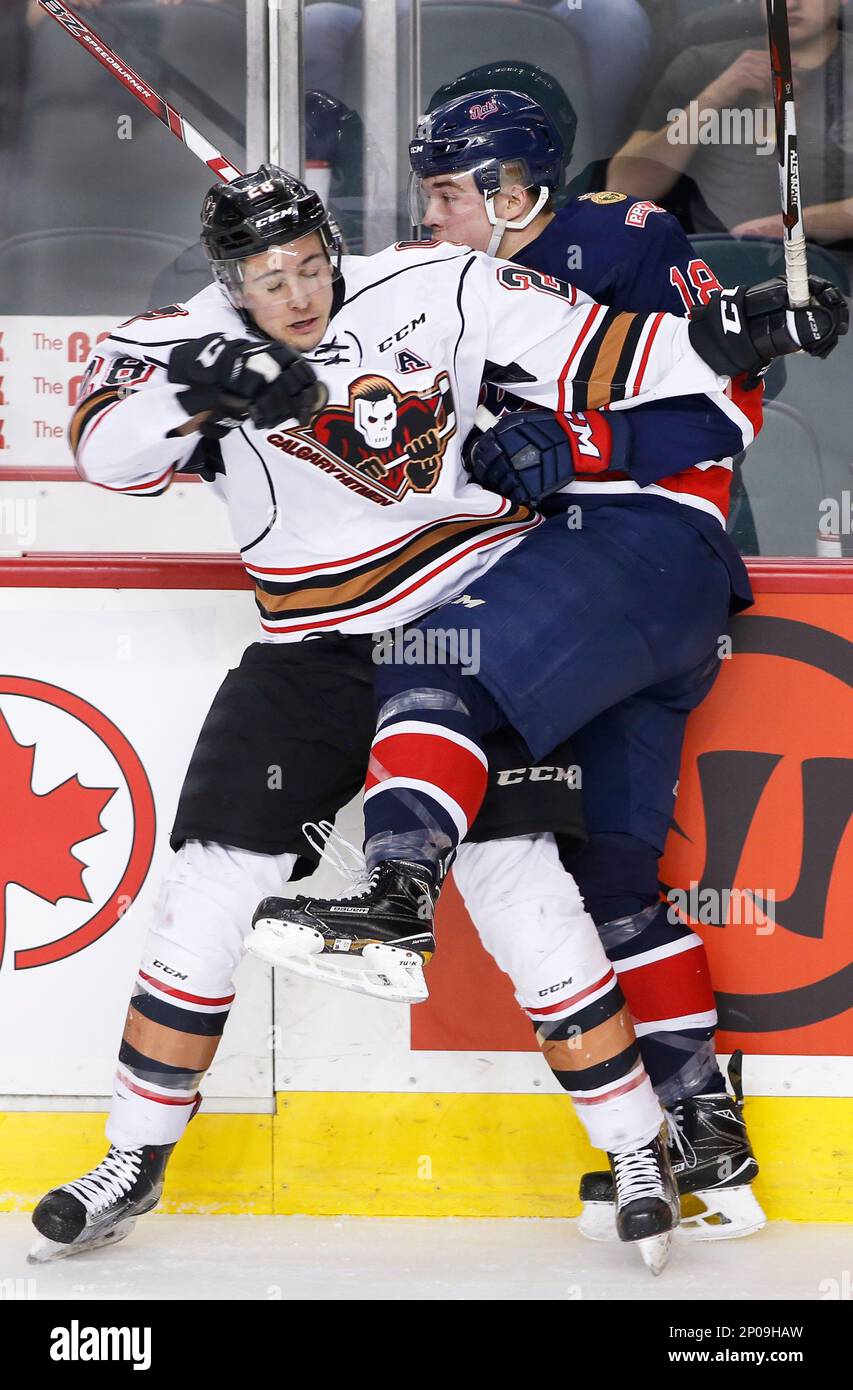 Regina Pats' Bryan Lockner, right, takes a hit from Calgary Hitmen's ...