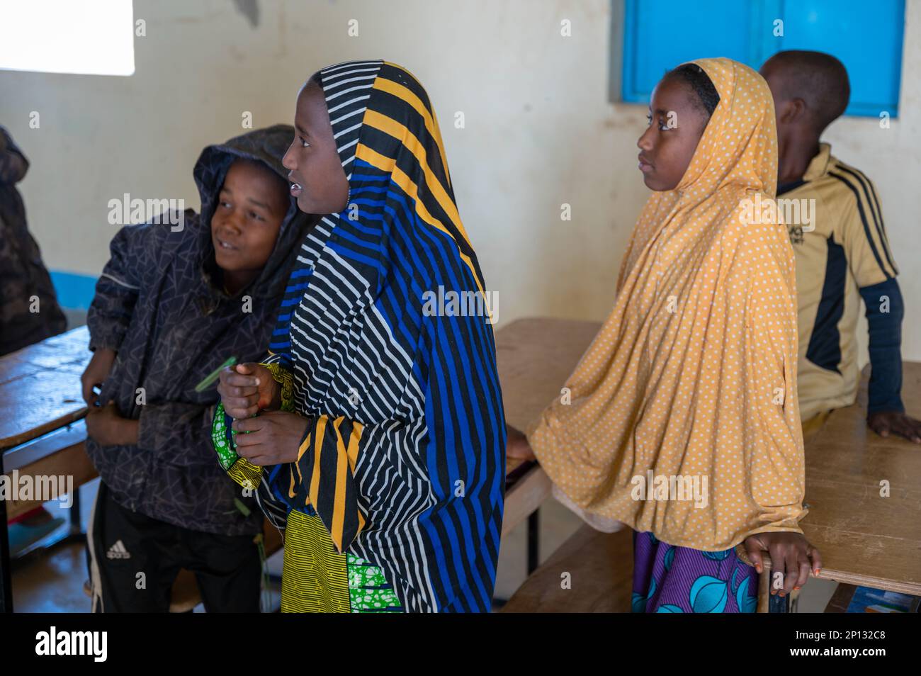 Schüler sehen, wie Schulpersonal Spenden in einer örtlichen Schule in der Nähe von Agadez, Niger ...