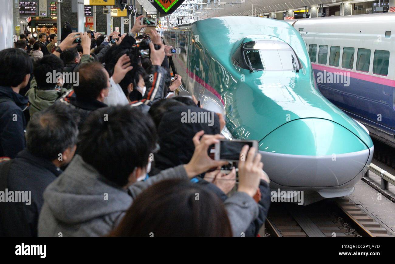 A crowd of train fans take photos of the first Shinkansen bullet train, leaving JR Tokyo Station ...