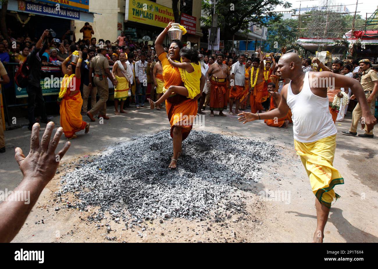 A Hindu devotee carrying her child,walks on burning coal during a ...
