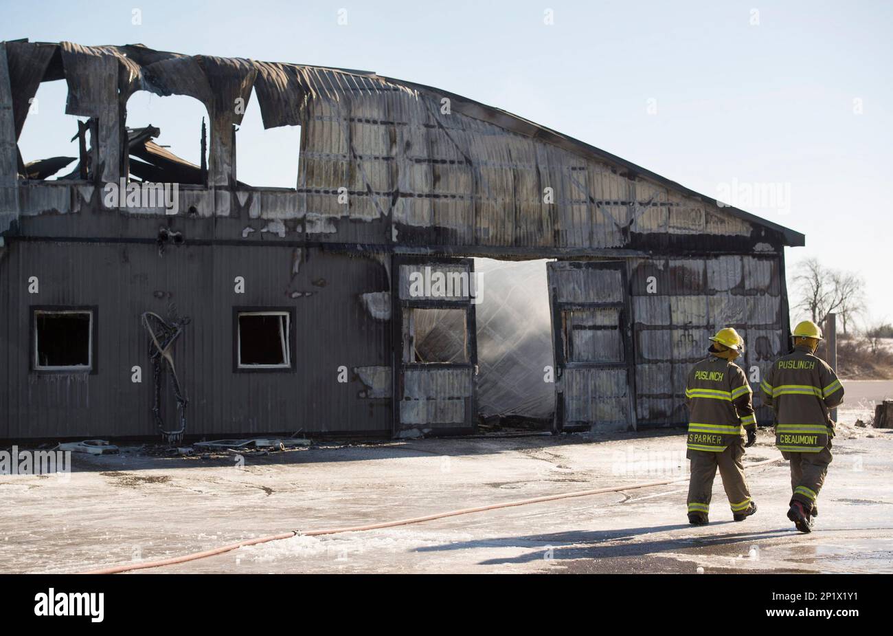 Firefighters walk past a barn that was destroyed by a fire at the ...