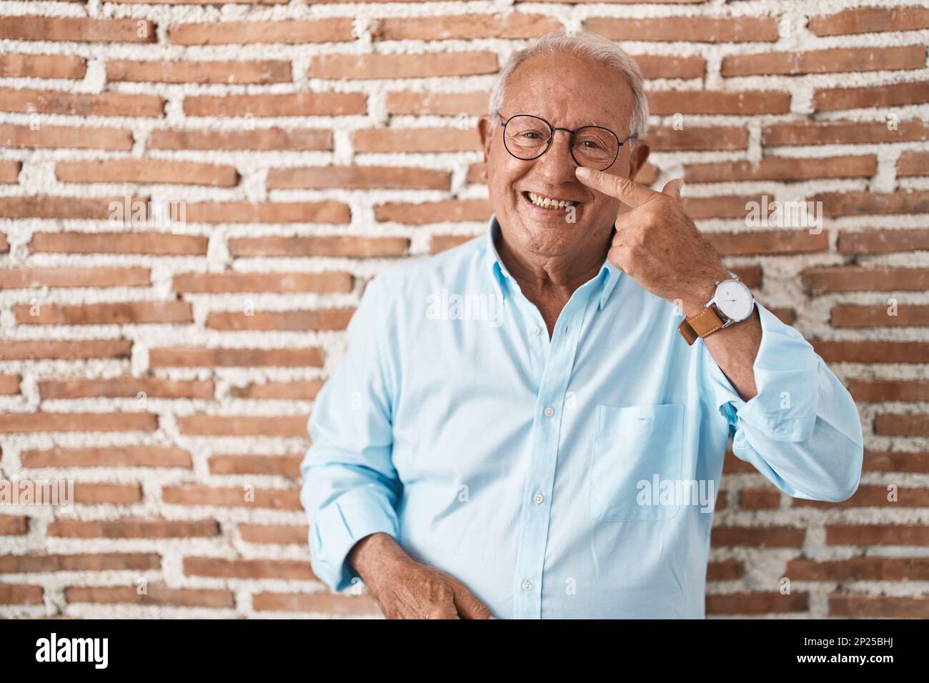 Ein älterer Mann mit grauen Haaren, der über einer Ziegelwand steht und ...