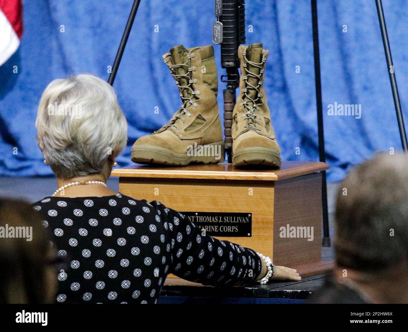A woman touches the boots on the battlefield cross for Gunnery Sgt ...