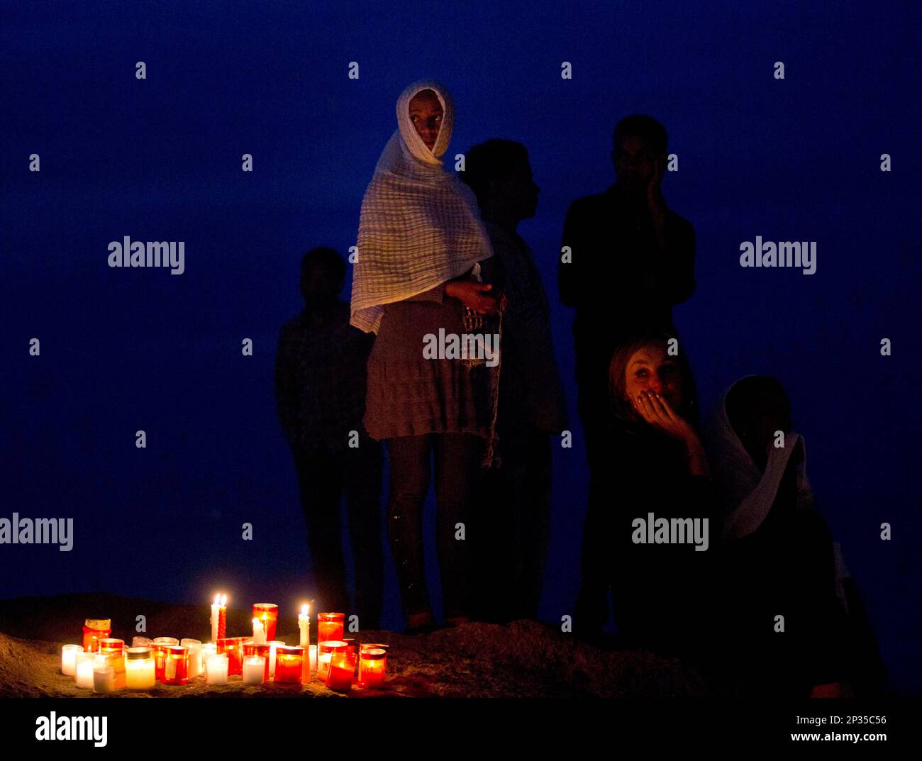 People pause by the sea during a candle light vigil in Sliema, in the ...