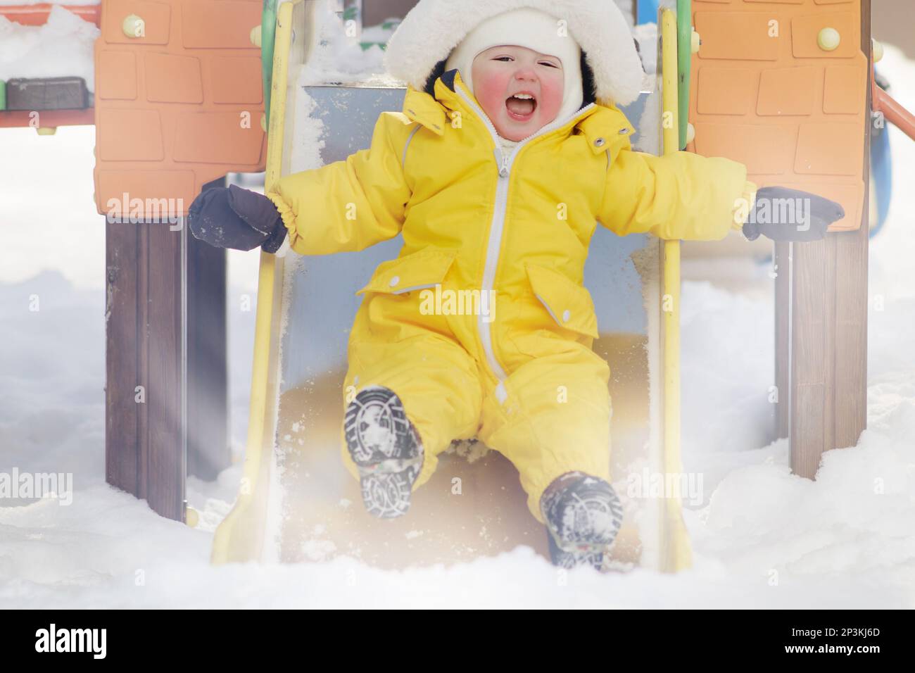 Der kleine Junge fährt auf einer Rutsche und spielt auf einem ...