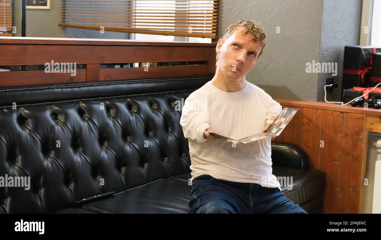 Ein junger Mann mit Behinderung sieht sich einen Katalog an, wenn er ...