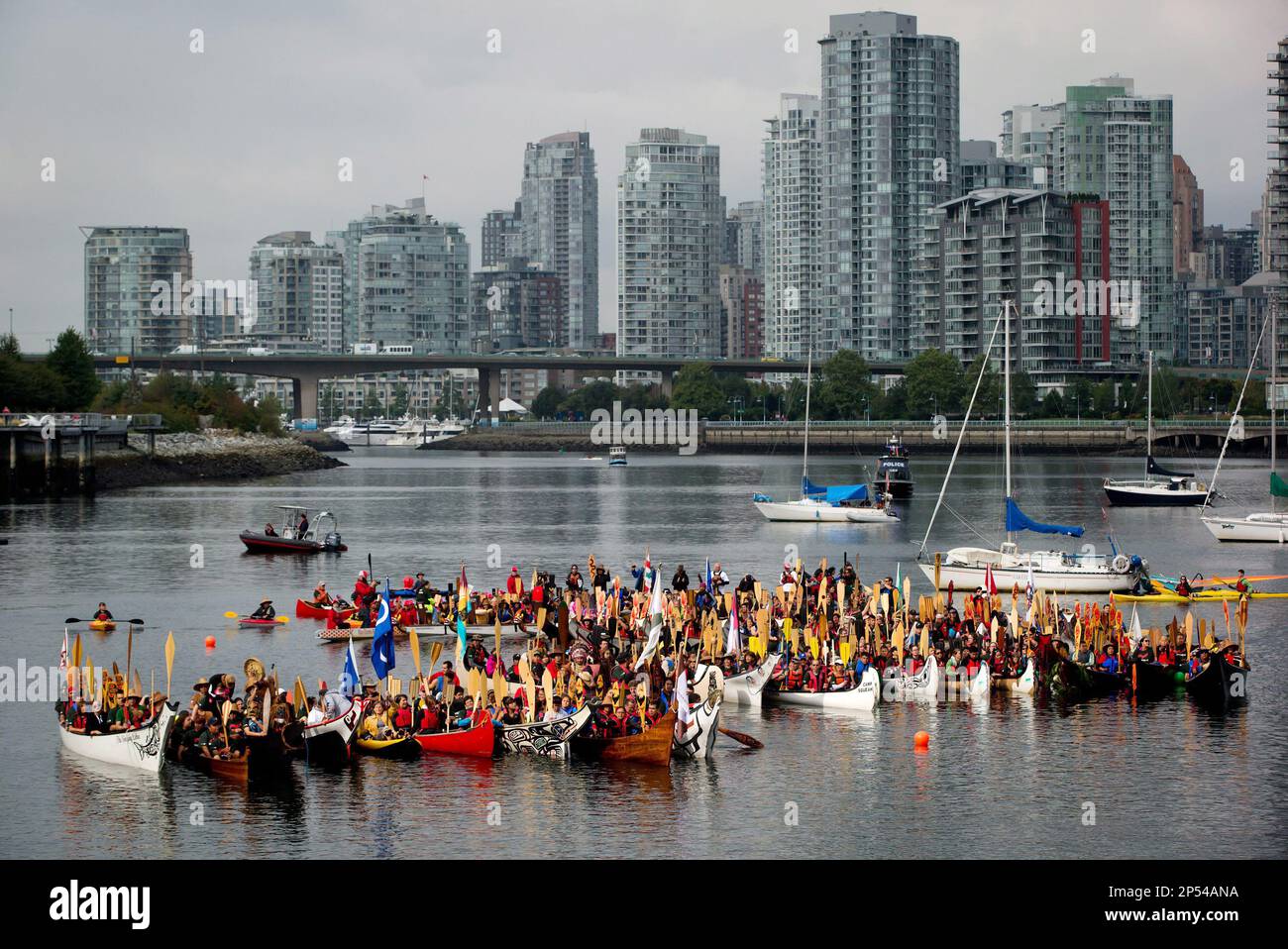 People on First Nations canoes raise their paddles on False Creek ...