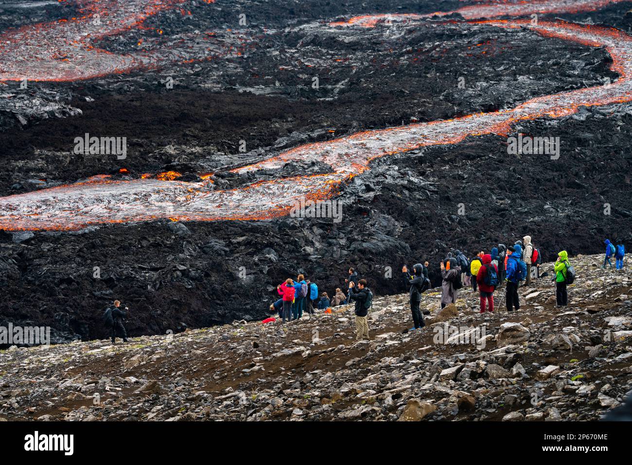 Touristen beobachten die fließende Lava am Vulkan Fagradalsfjall, der ...