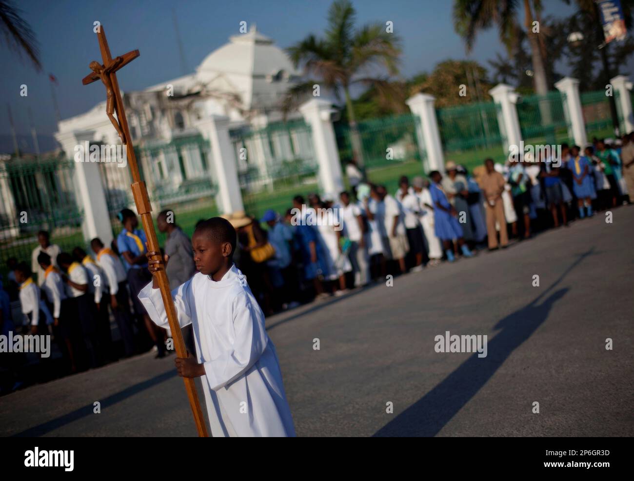 A child carries a wooden cross in front of the the earthquake-damaged ...
