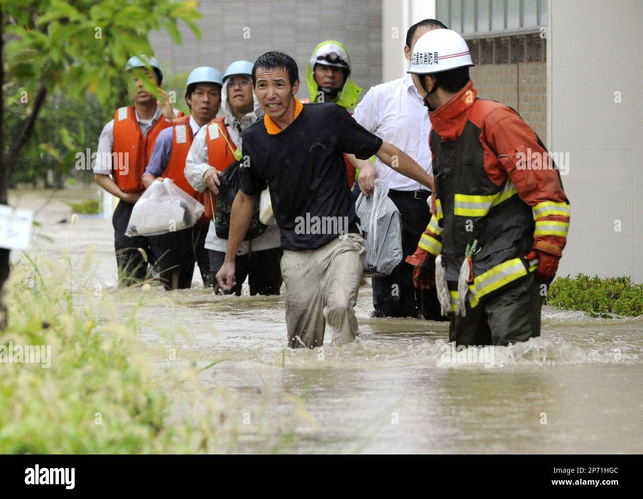 Local residents wade through a flooded street caused by approaching ...