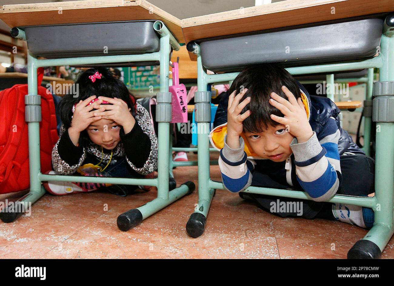 South Korean elementary school students crouch underneath classroom ...