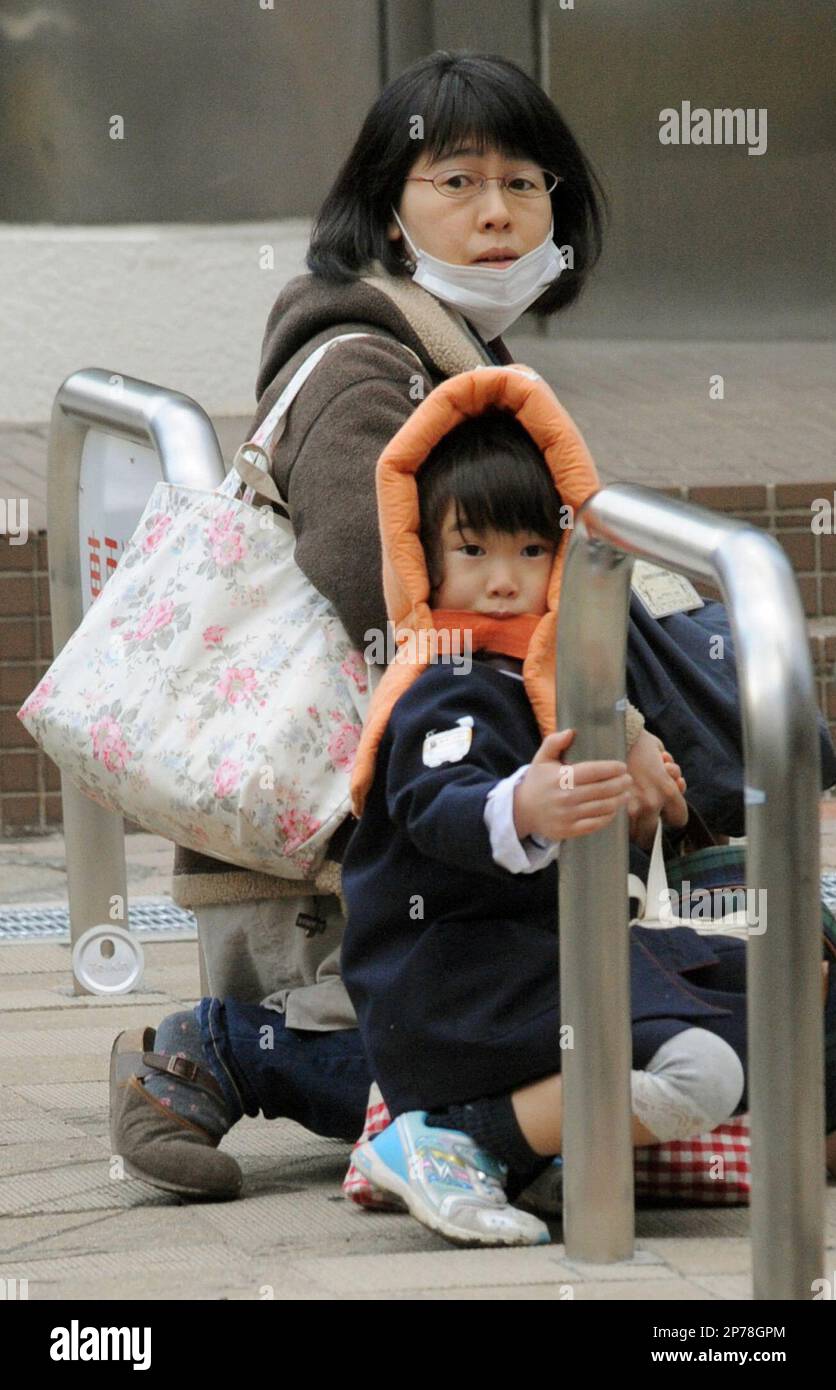 A mother and child crouch on a street in Tokyo while an earthquake hits ...
