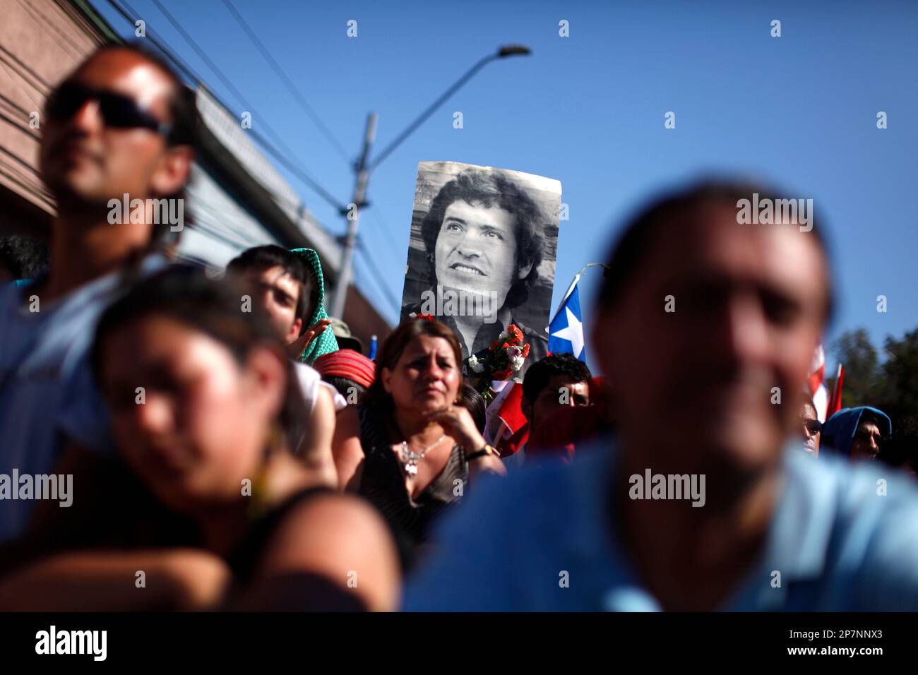 A photograph of Chile's folk singer Victor Jara is seen between people ...