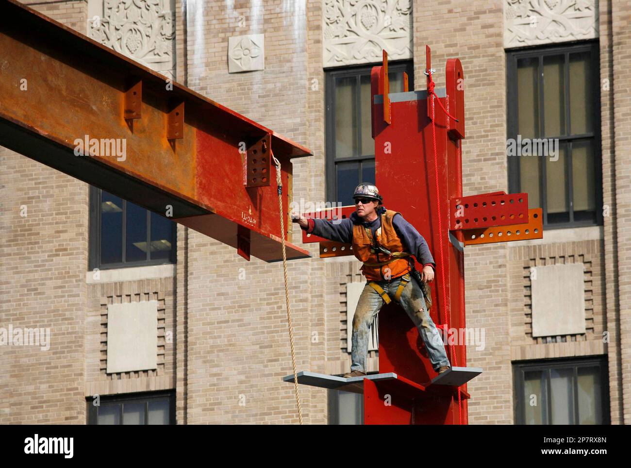 An ironworker reaches for a steel beam suspended by a crane at One ...