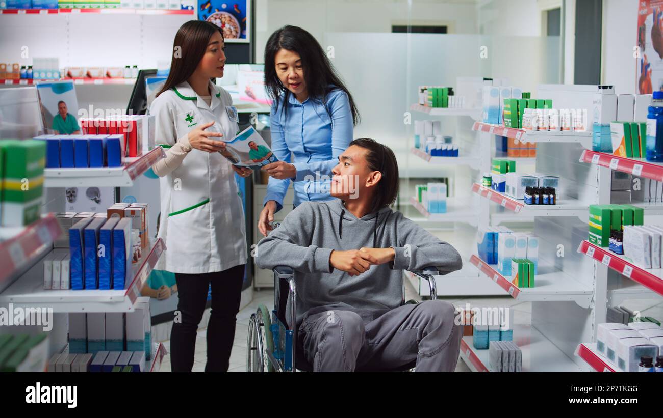 Männlicher Mandant im Rollstuhl und Hausmeister, der mit Apotheker ...