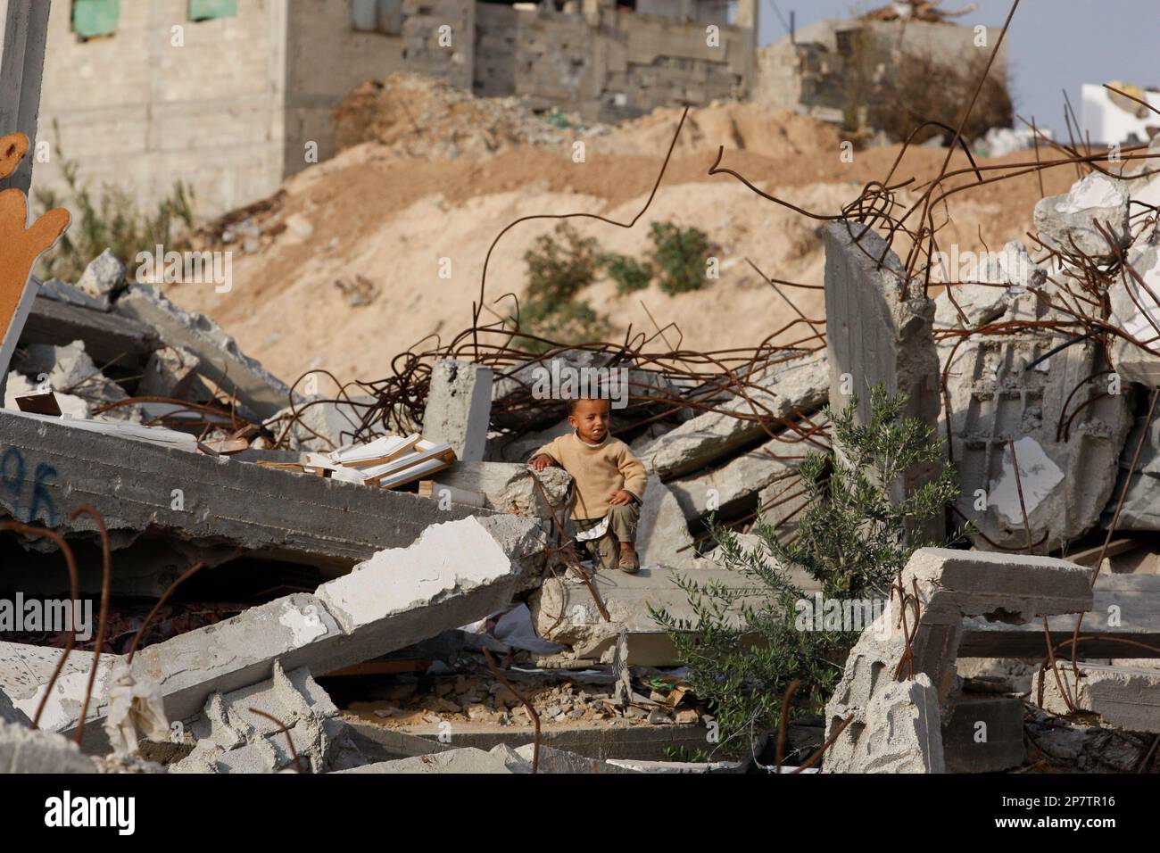 A Palestinian boy stands in the remains of a house destroyed during ...