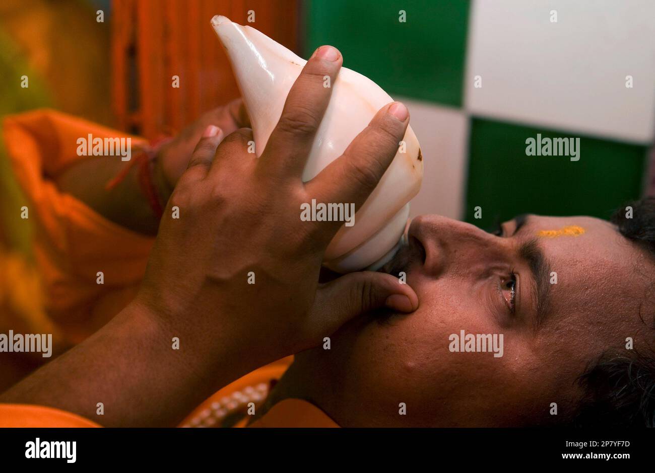 A Hindu priest blows a conch shell horn on the occasion of Hanuman ...