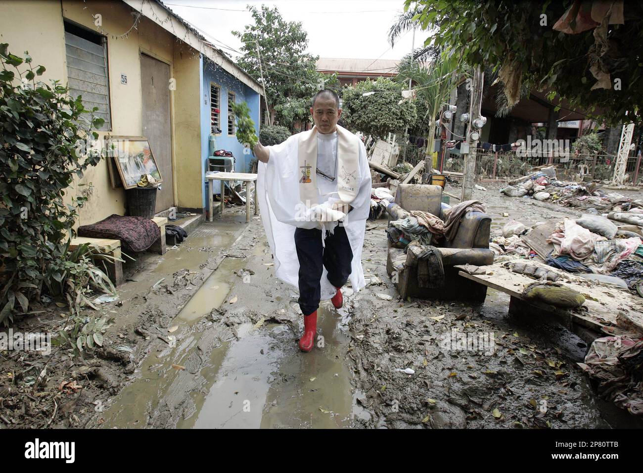 Catholic priest Father Robert Reyes uses a tree branch as he sprinkles ...
