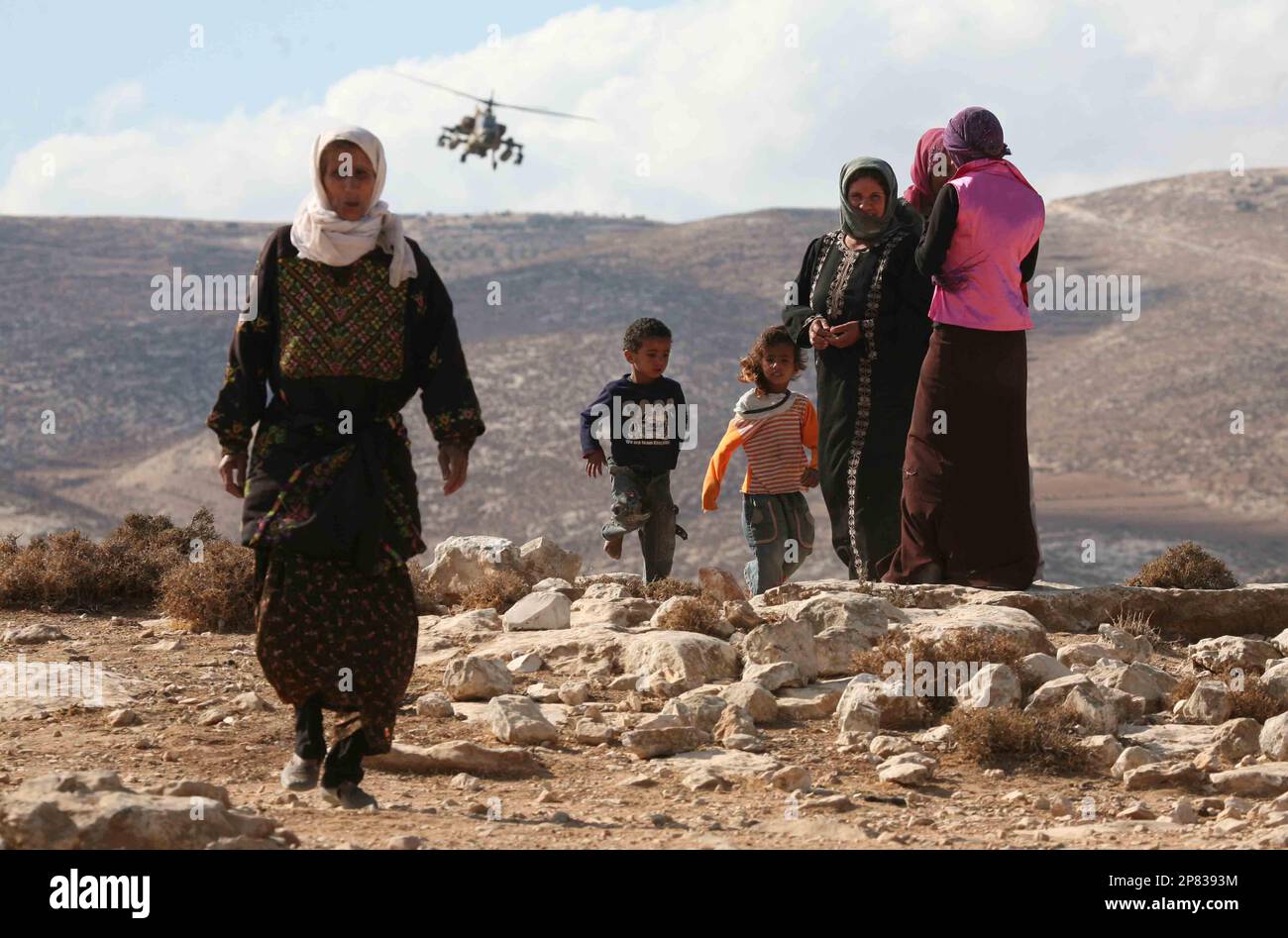 A Palestinian family walk on a hill as an Israeli air force combat ...