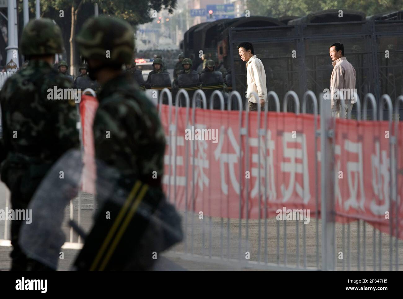 Chinese people walk past Chinese paramilitary police officers standing ...